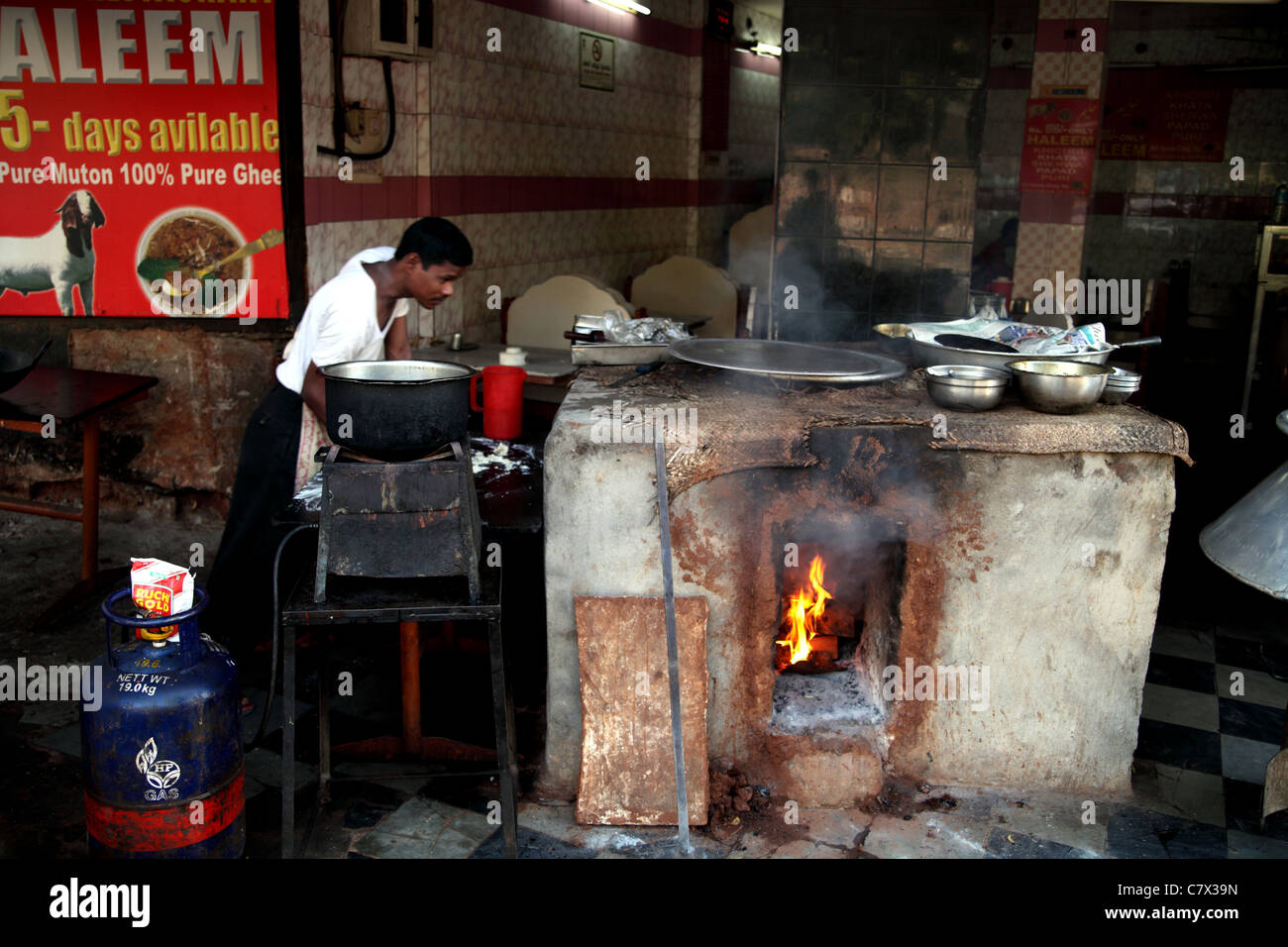 Portrait of young Indian man mixing flour and water on large plate in ...