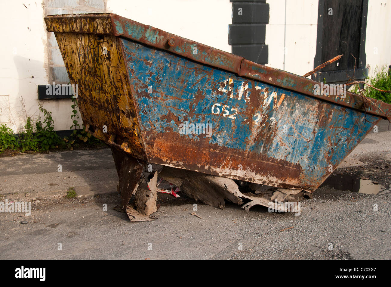 Badly corroded and damaged skip with the bottom fallen out, dumped in a ...