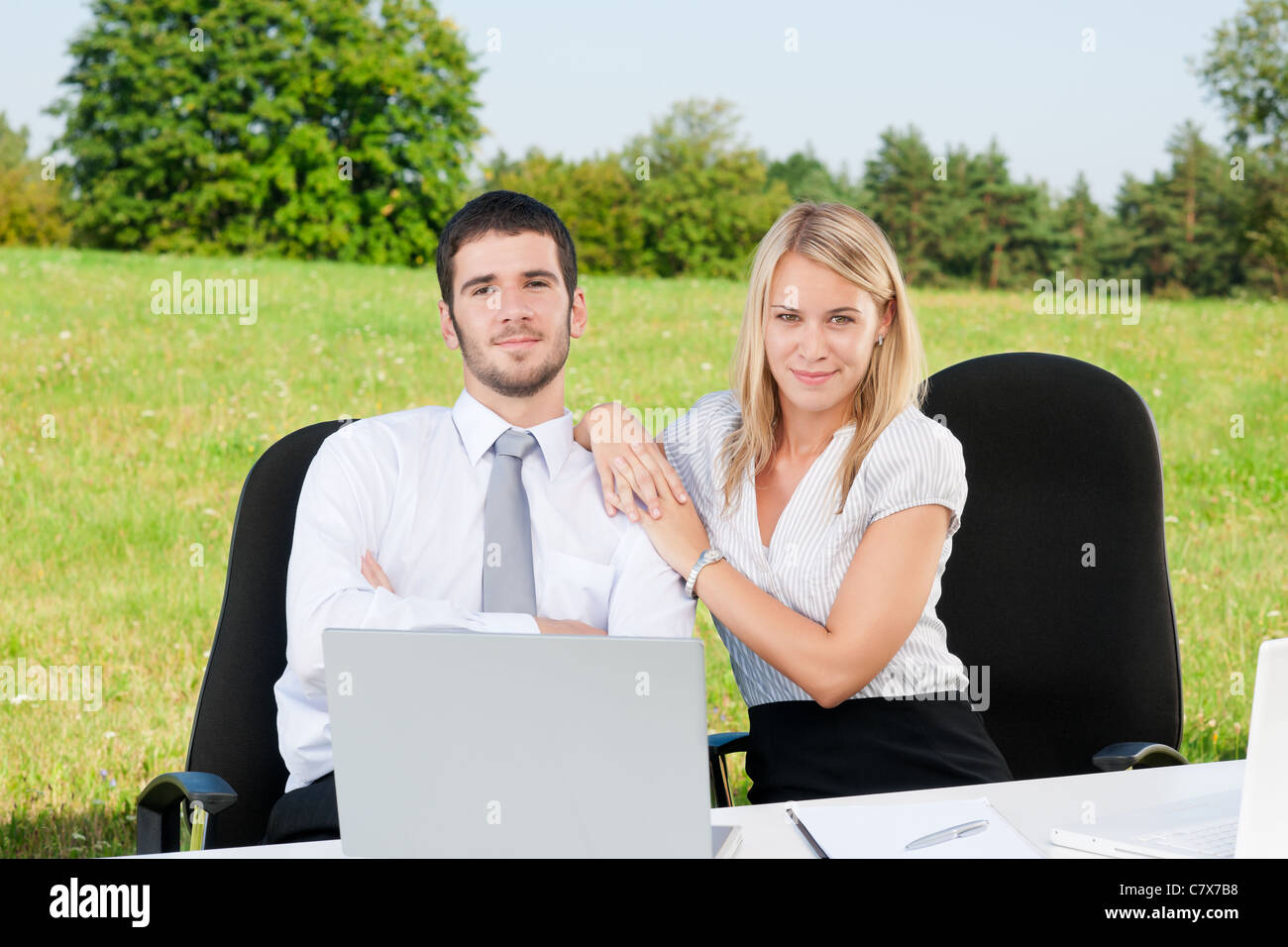 Young business colleagues in nature office sitting behind table ...