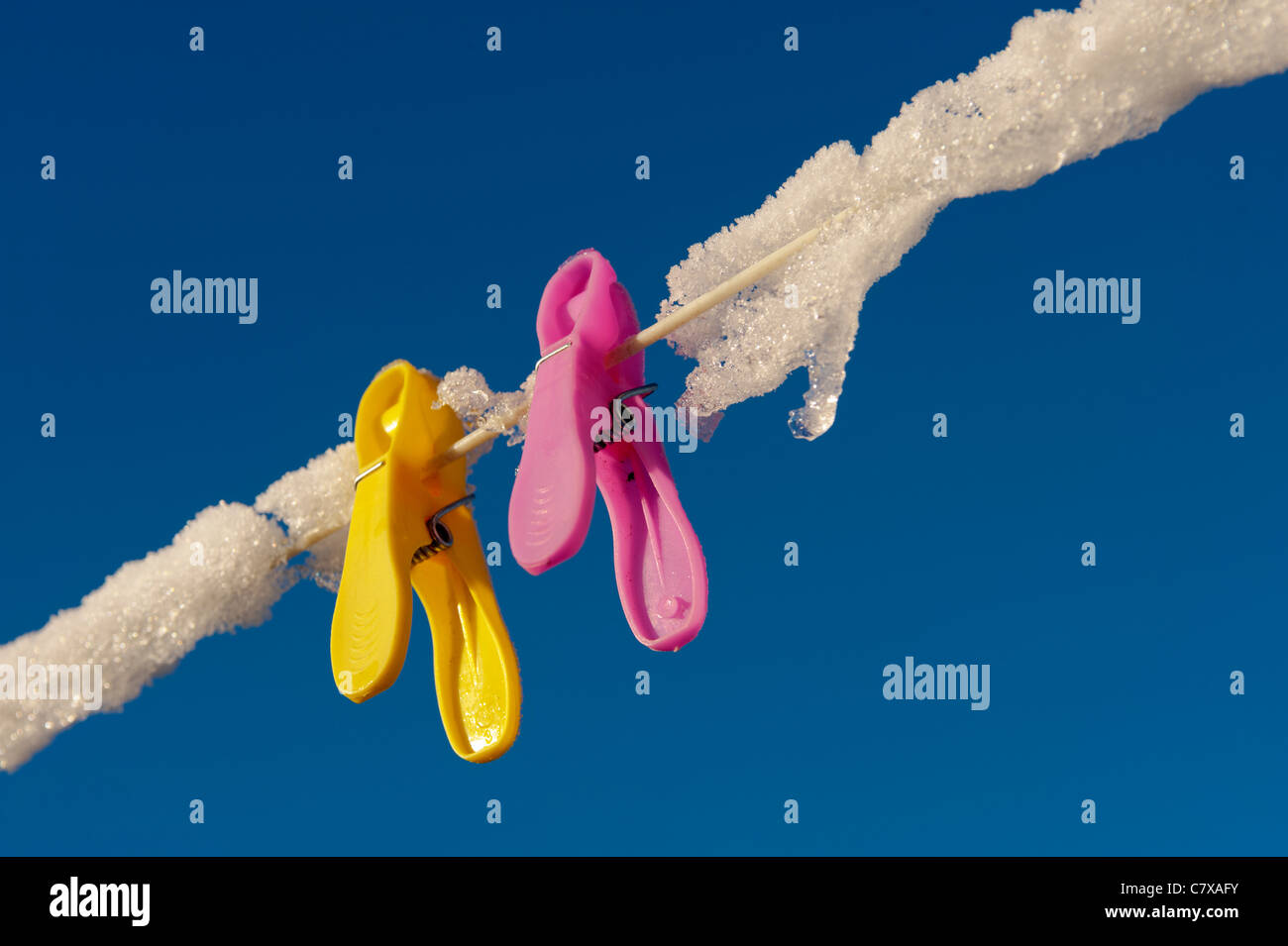 Colorful clothes pegs on a clothes line covered in ice in winter with a ...
