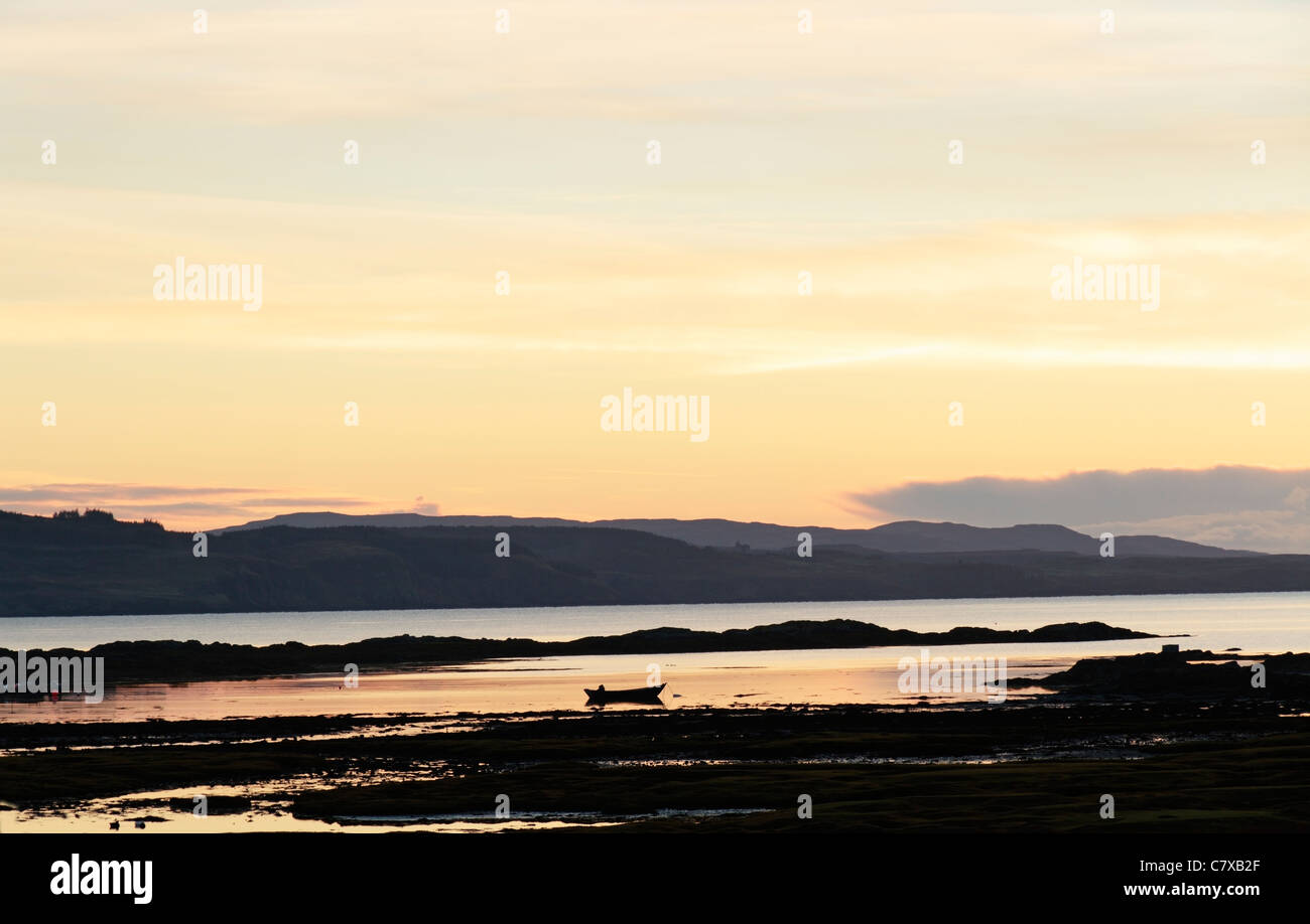 Silhouette of rowing boat moored in sunset within rocky inlet at ...