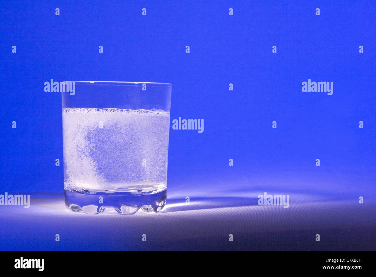Soluble tablet in a glass of water, blue background Stock Photo - Alamy