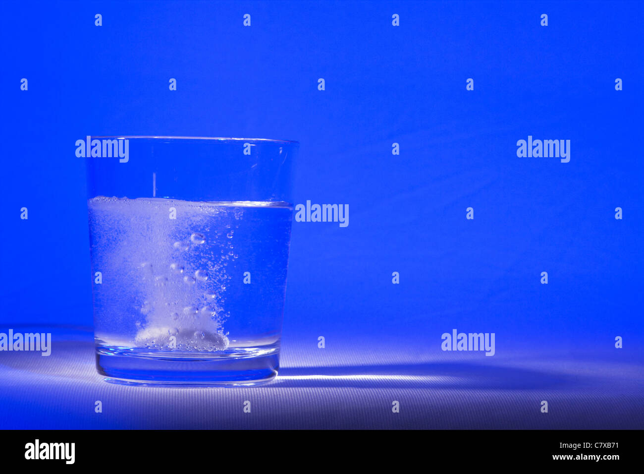 Soluble tablet in a glass of water, blue background Stock Photo - Alamy