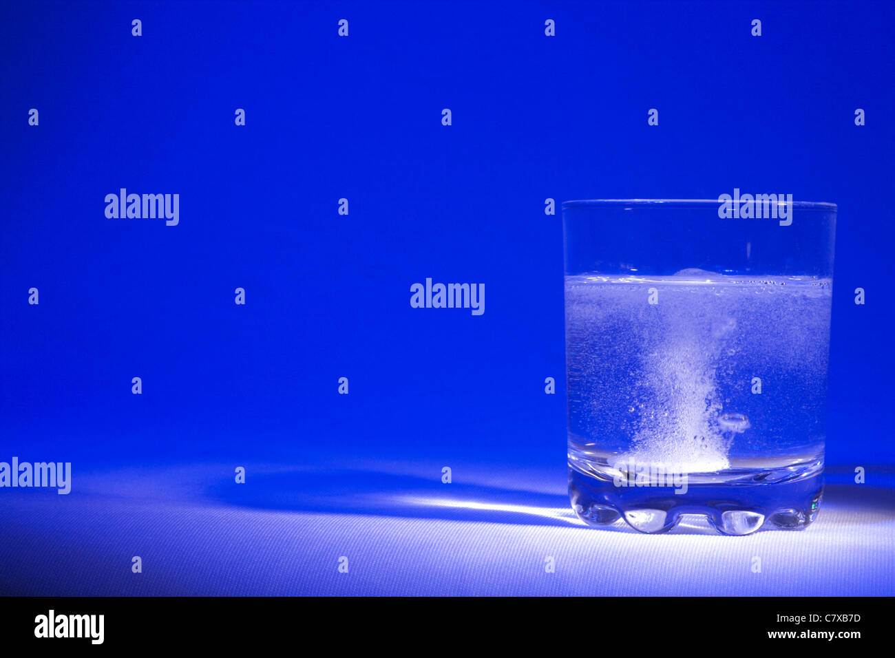 Soluble tablet in a glass of water, blue background Stock Photo - Alamy