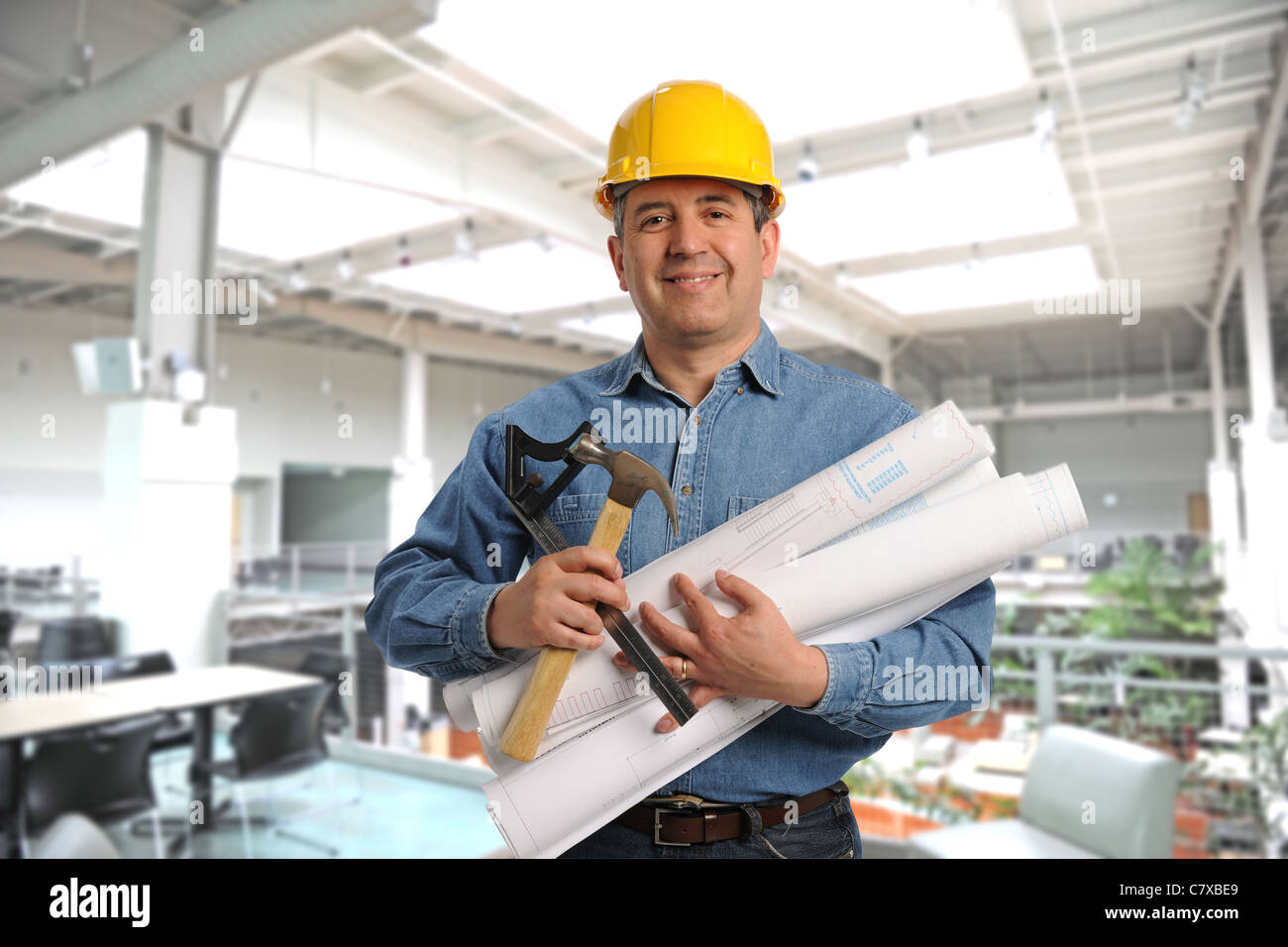 Man holding plans and tools inside a modern building Stock Photo - Alamy
