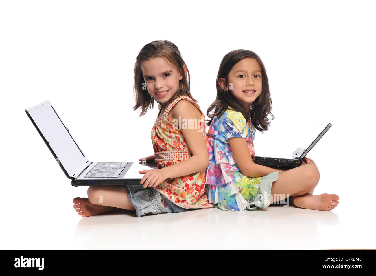 Two little girls with laptop computers isolated on a white background ...