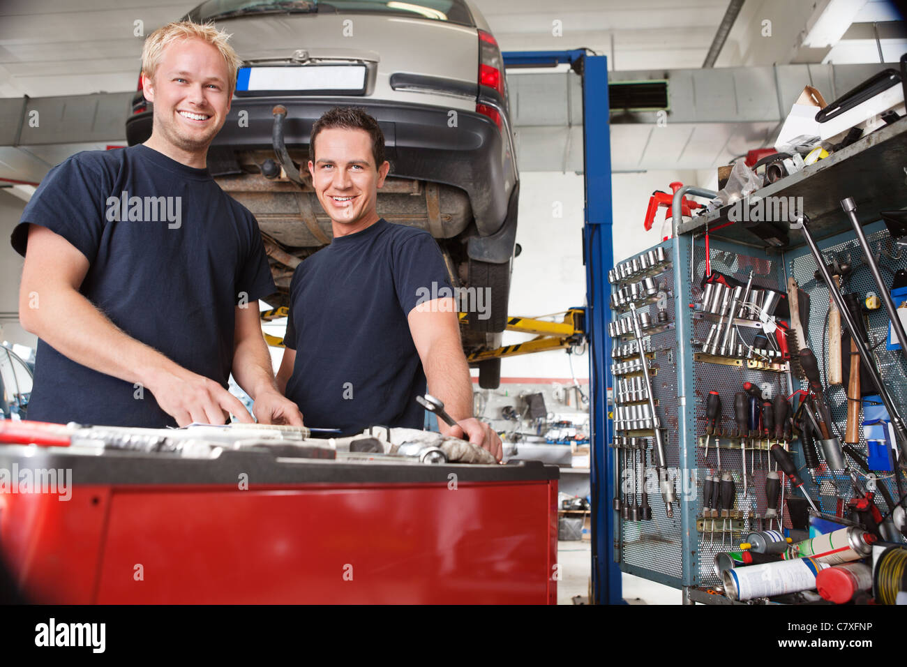 Two happy mechanics standing in garage Stock Photo - Alamy
