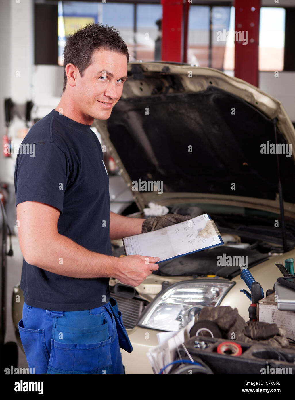 Portrait of a mechanic, looking at the camera with a service report in ...