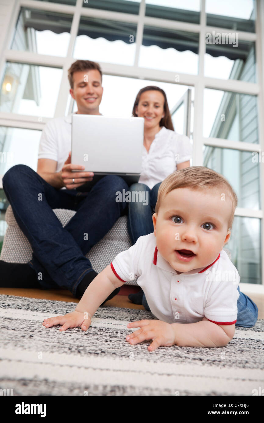 Portrait of cute child with parents using laptop in the background ...
