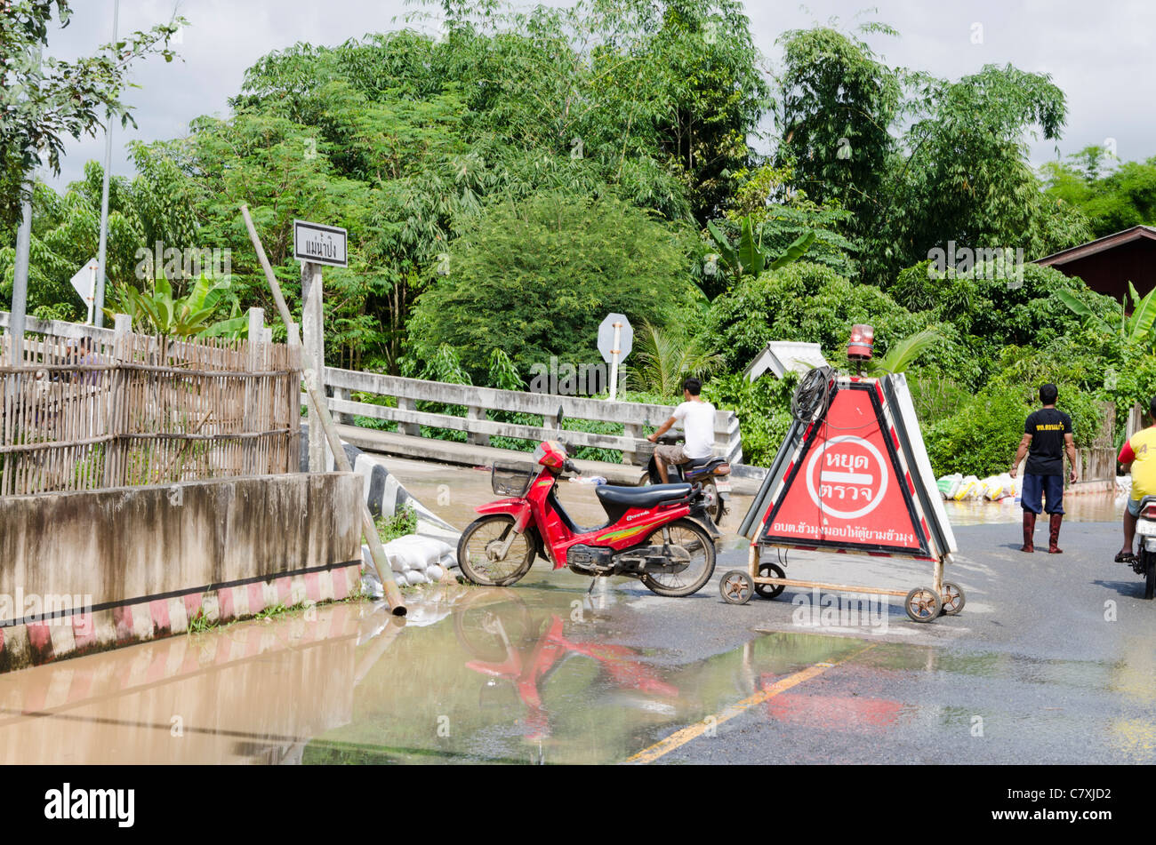 Large red triangular warning sign in Thai language on road at flooded ...