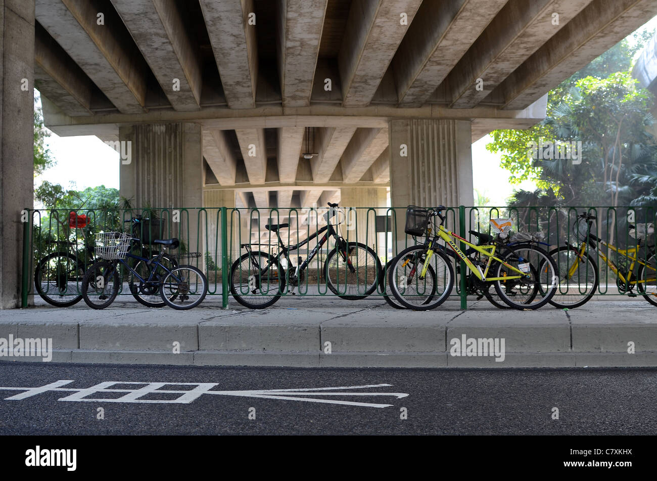 Bicycles are chained to a railing under an overpass near Siu Lek Yuen ...