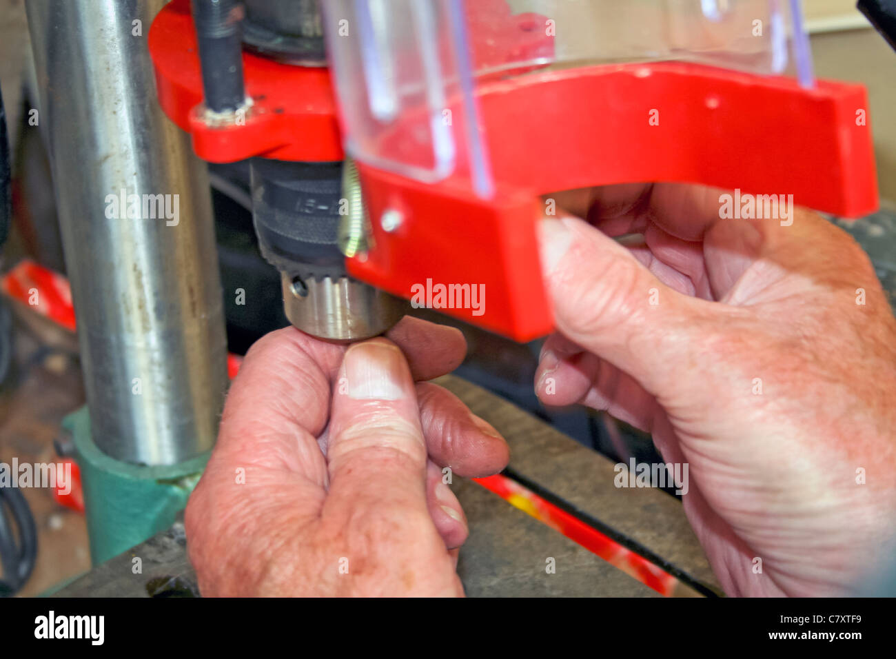 An engineer adjusts the chuck of an electric pillar drill in a close-up ...