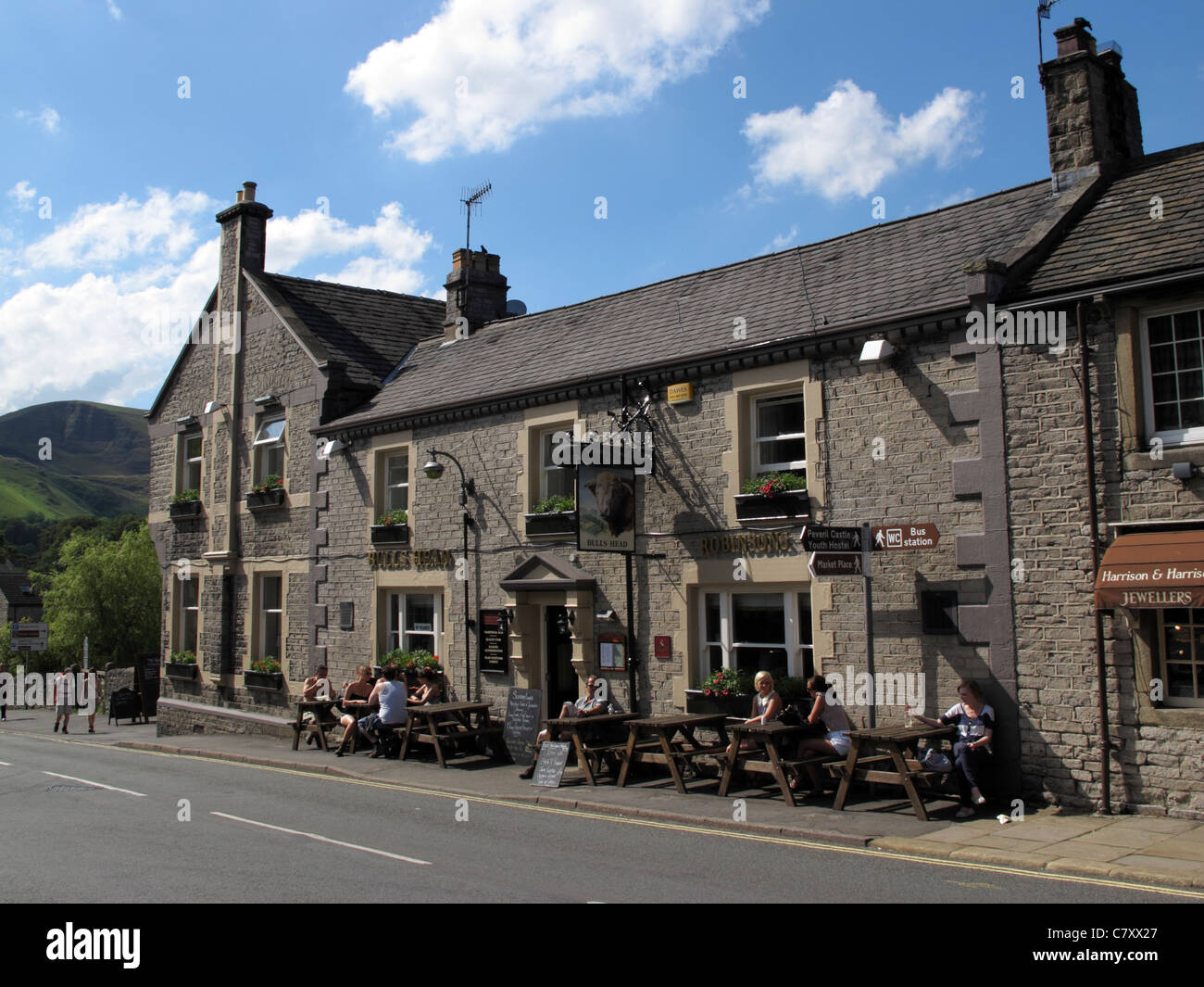 People sitting outside a Public house in Castleton in the Peak district ...