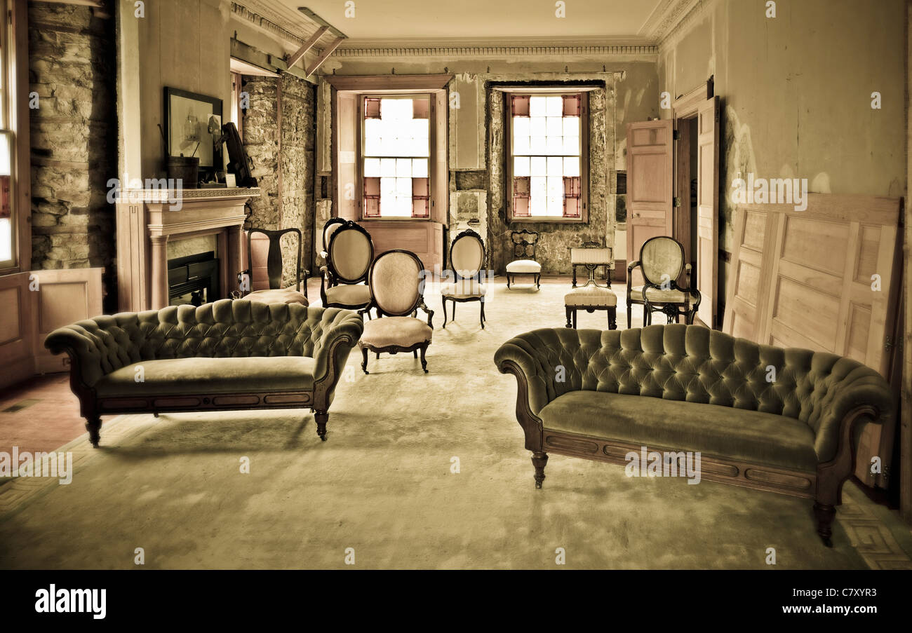 a collection of chairs and sofas in a run down room Stock Photo - Alamy