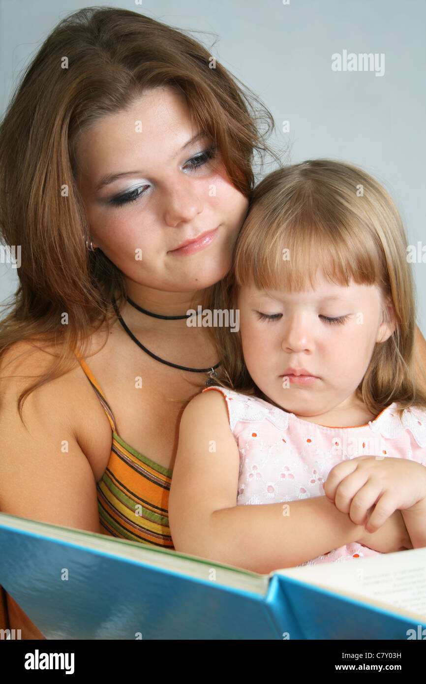 Two sisters different ages read the large book Stock Photo - Alamy