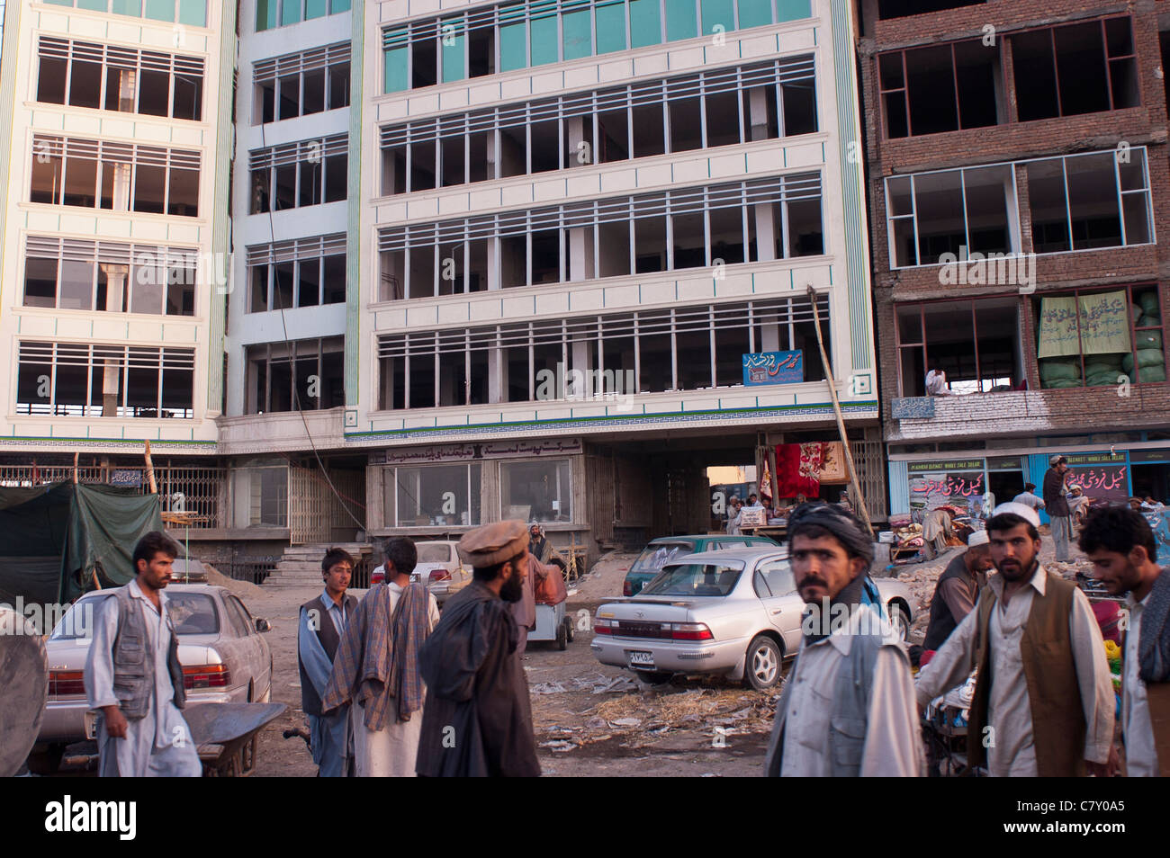 Men walk by a partially completed office building in central Kabul ...