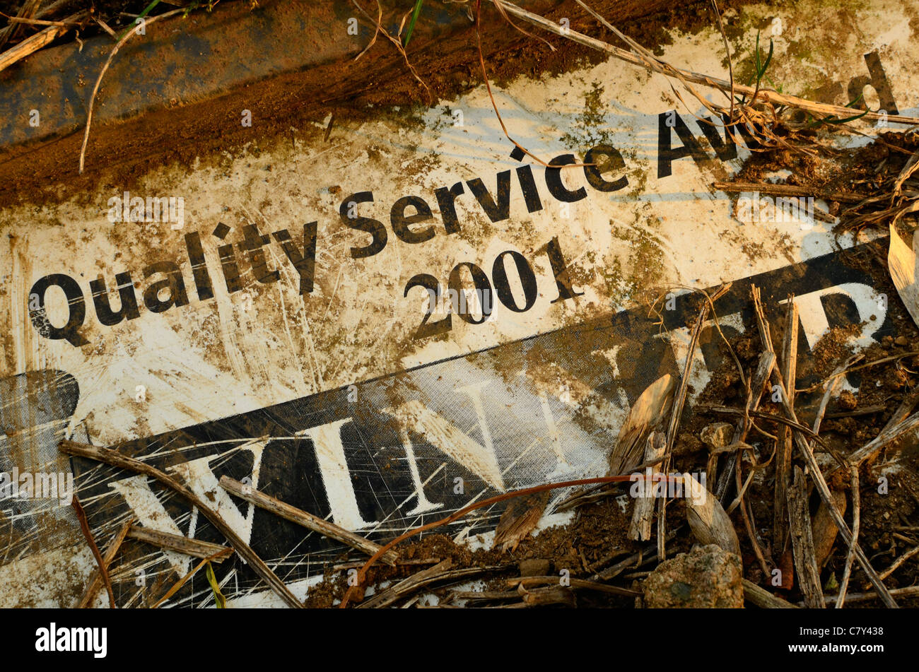Discarded 'quality award winner' sign, covered in dirt and debris Stock ...