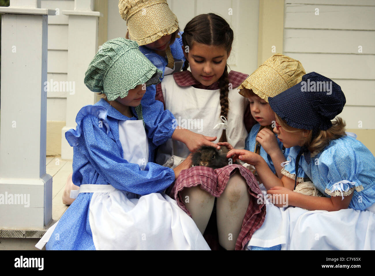 Girls gathered on a porch around a bunny Stock Photo - Alamy