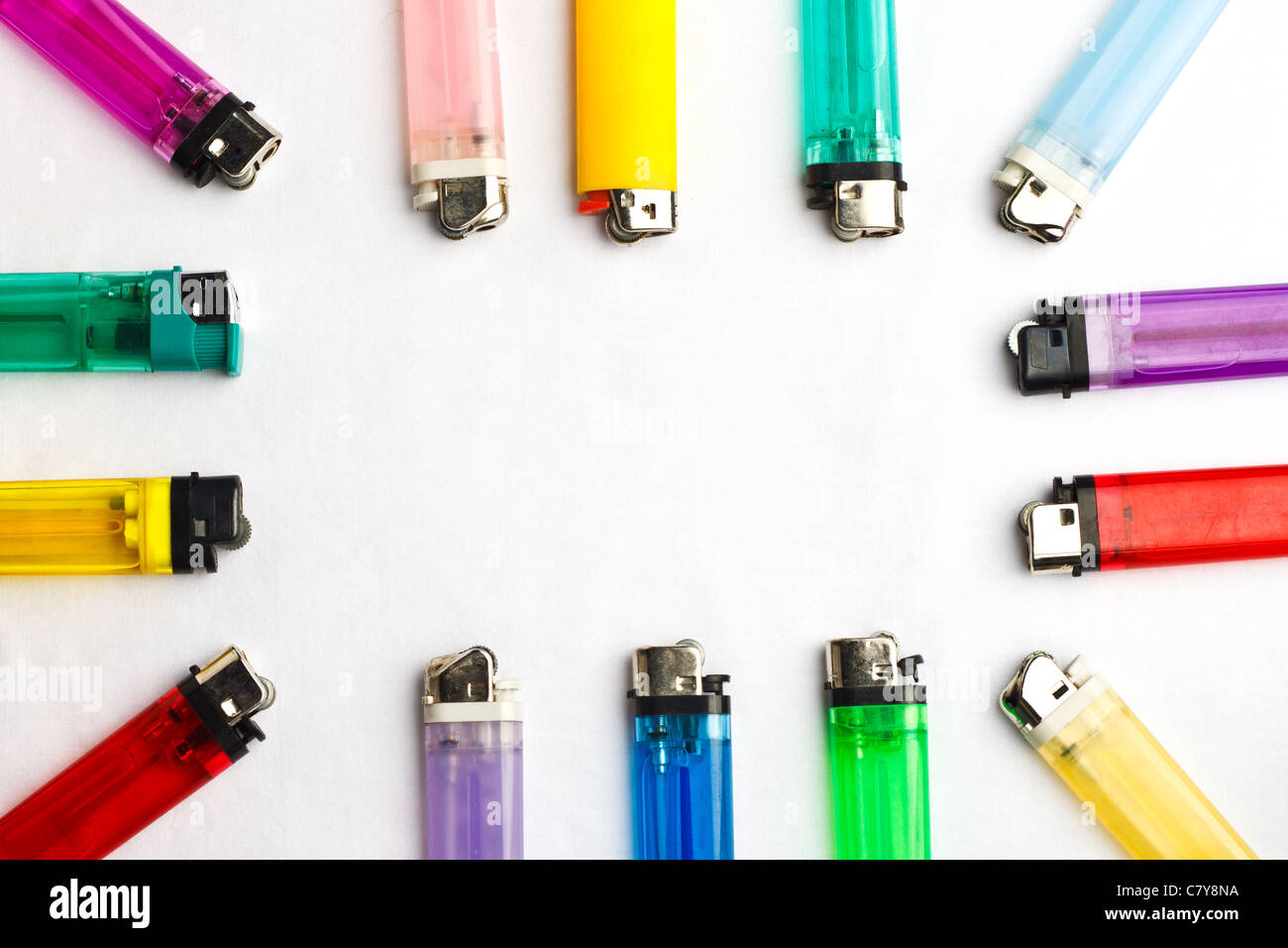 Colorful assortment of disposable lighters bordering a white background ...