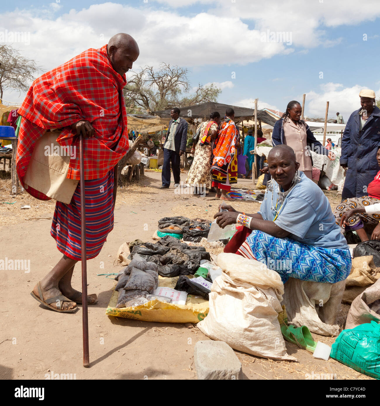 African man dressed in traditional Massi clothing at a market stall ...