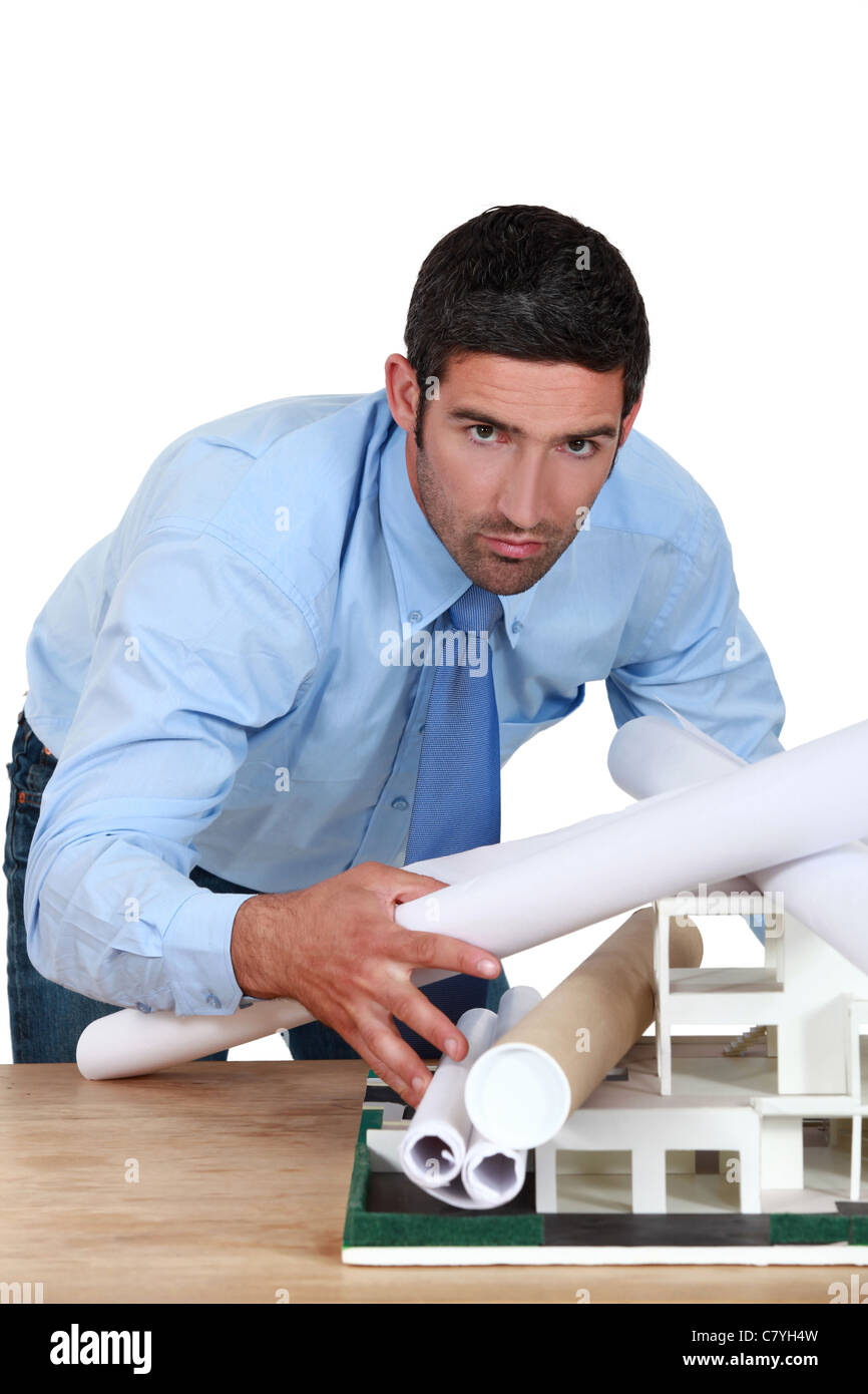 young architect bending over desk with blueprints and model Stock Photo ...