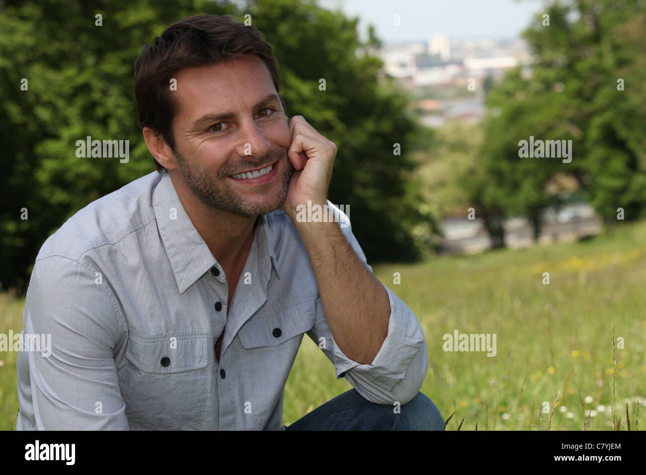 Smiling man sitting in a park Stock Photo - Alamy