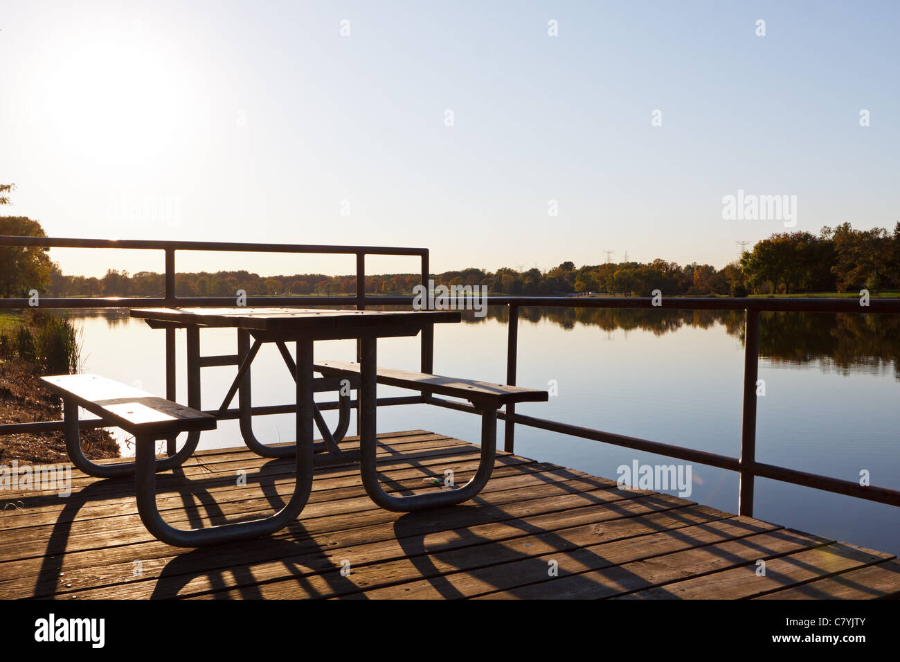Picnic table on a lakeside pier during sunset Stock Photo - Alamy