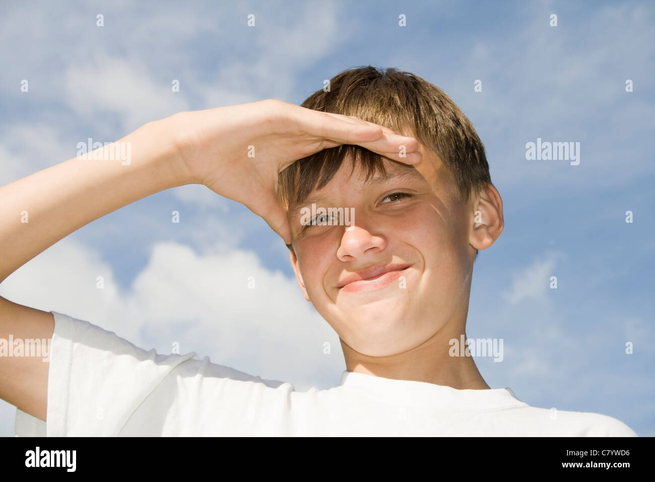 Happy lad portrait shadowing his eyes from the bright light of the sun ...