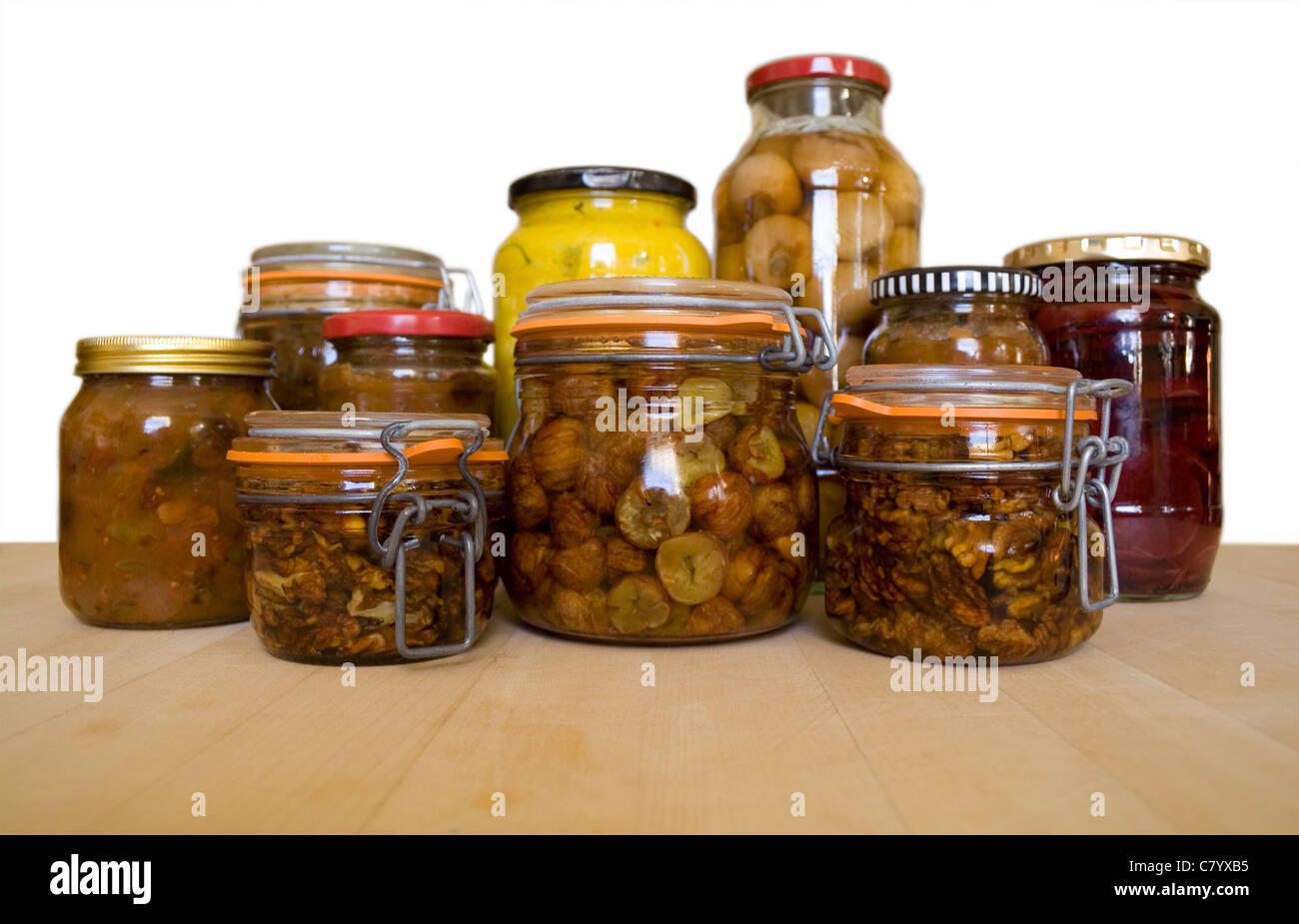 Home preserves and pickles on wooden surface with white background and ...