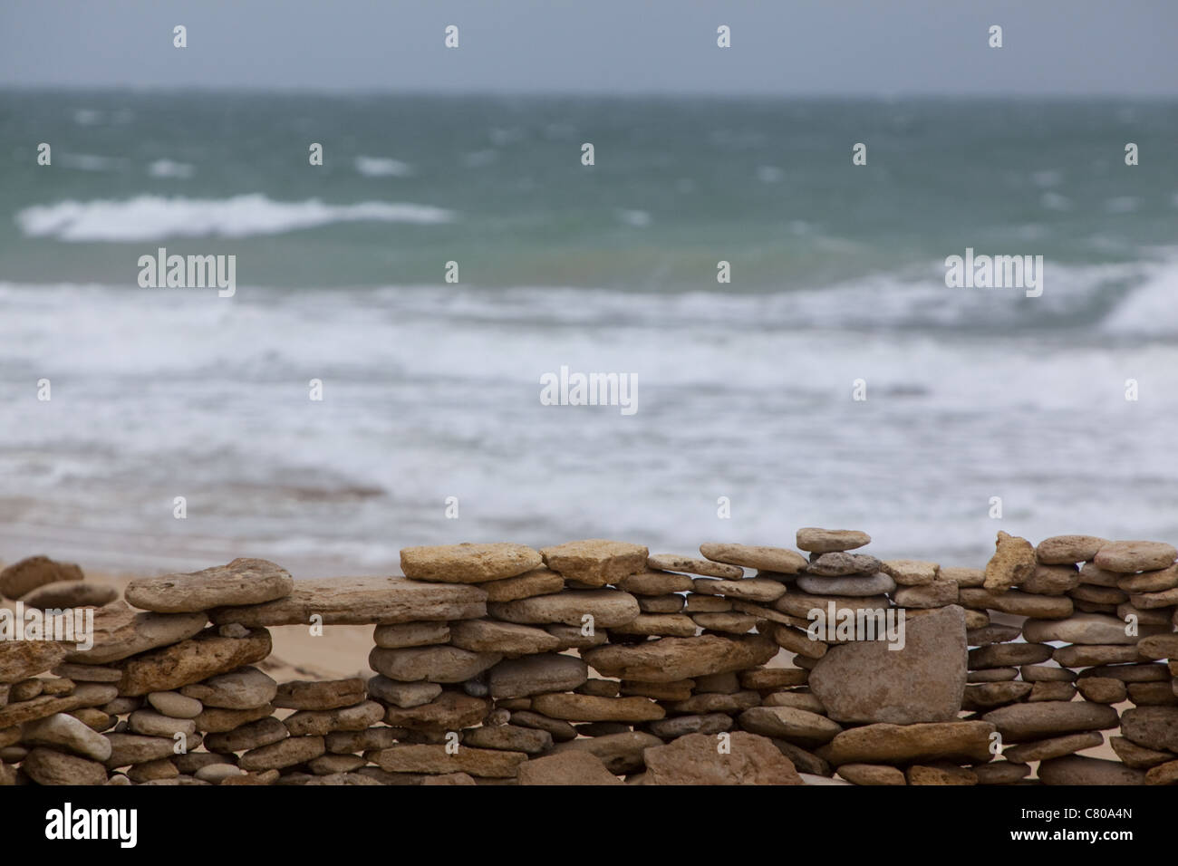 Colour photograph of a man made stone wall against the Atlantic Ocean ...