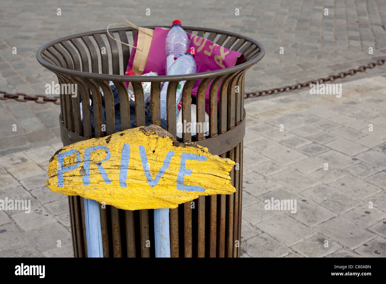 An ironic image of an iron garbage pail with a sign in front of it ...