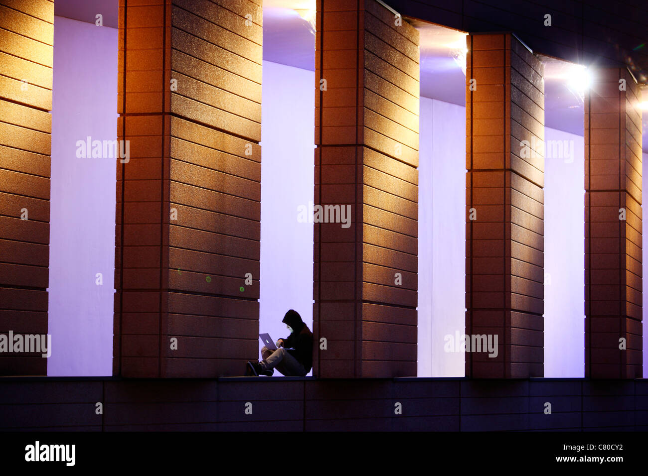 Computer user, hacker, sits conspiratorially, outside, with a laptop ...