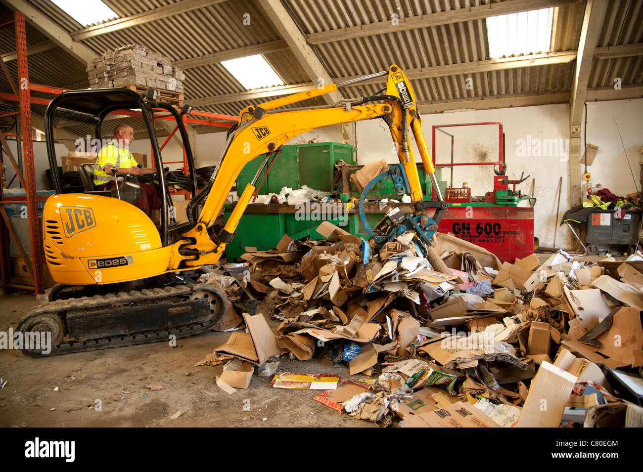 A worker compacting waste cardboard into bales ready for recycling. UK ...