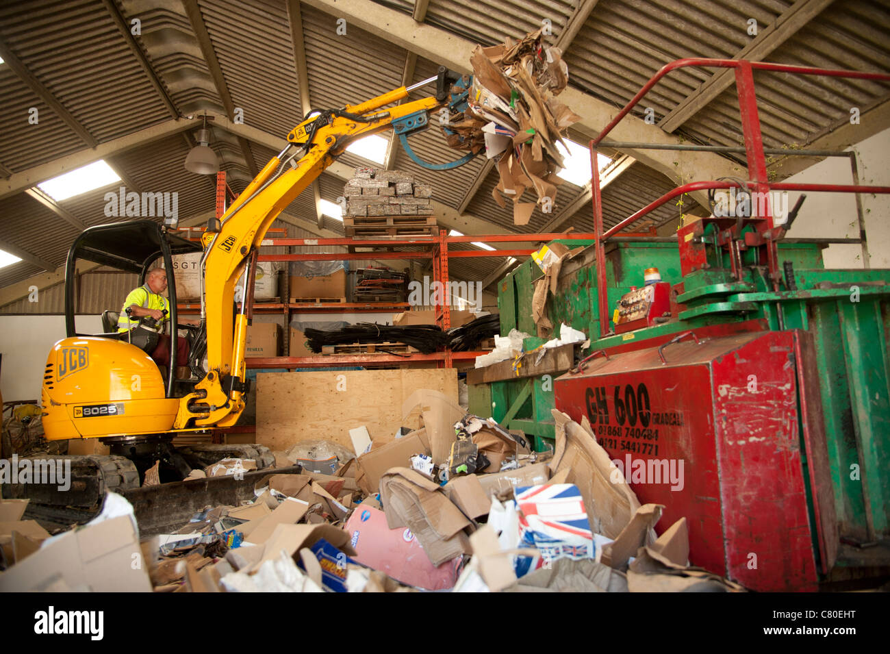 A worker compacting waste cardboard into bales ready for recycling. UK ...