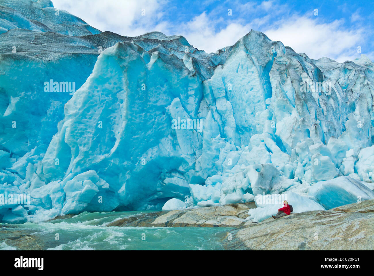 Norway Nigardsbreen glacier Woman in red coat sitting by Nigardsbreen ...