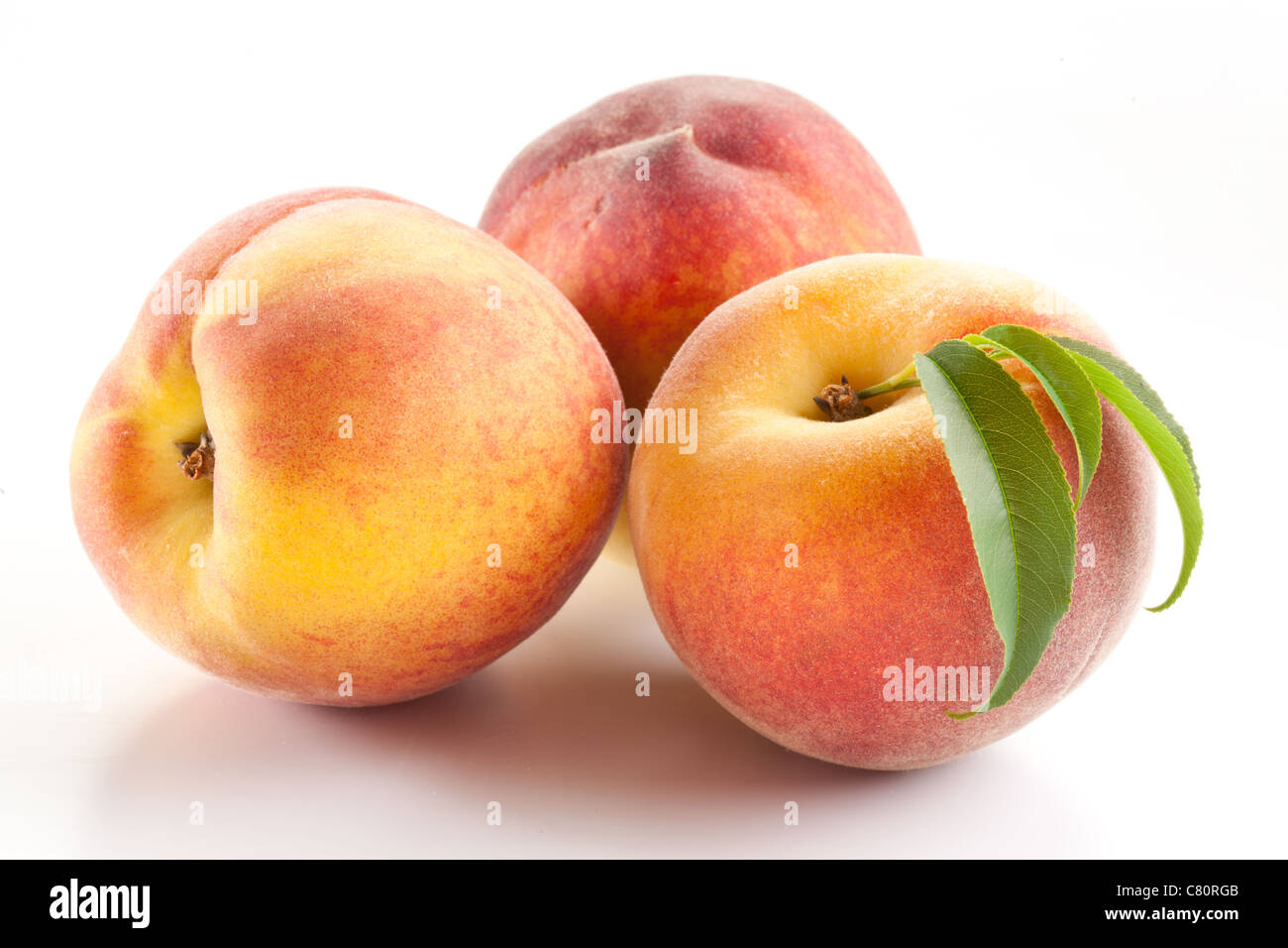 Three ripe peach with leaves on white background Stock Photo - Alamy
