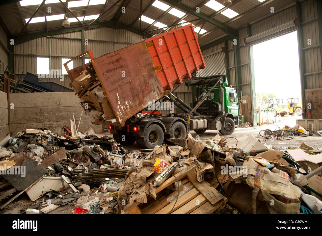 A large skip dumpster truck lorry unloading waste at a recycling centre ...