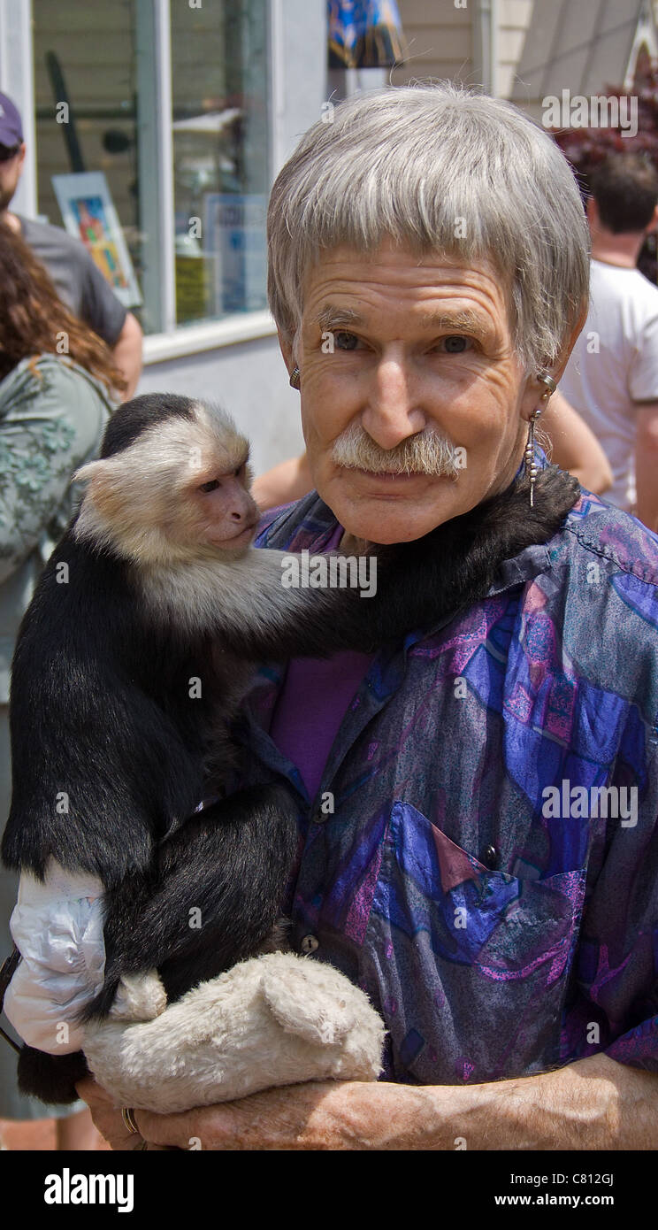 Older man holding his pet monkey at a street fair Stock Photo - Alamy