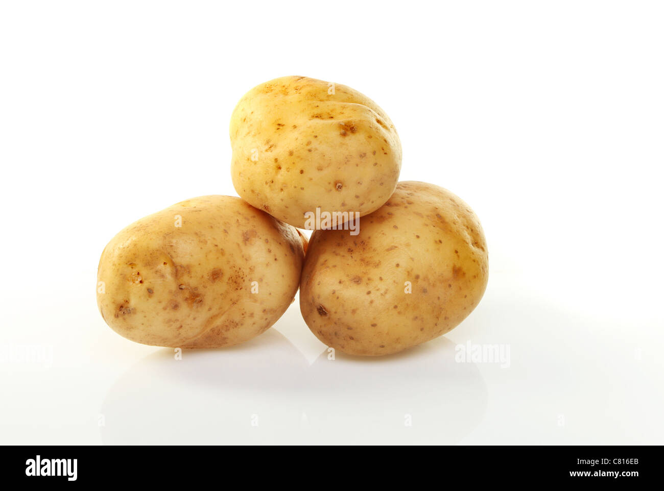 Stack of three washed new potatoes with soft shadows against a white ...