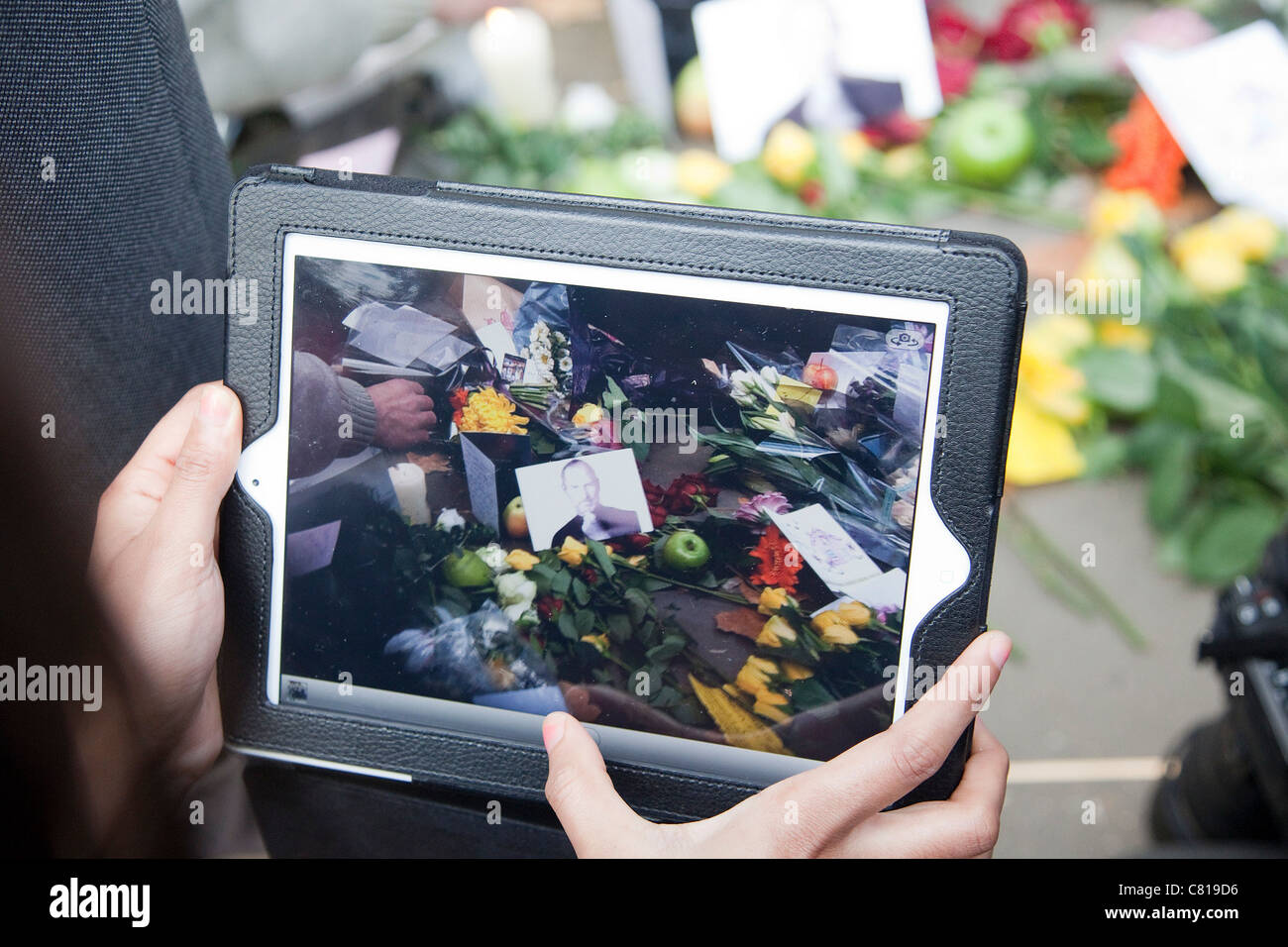 A young woman takes a picture of the tributes to the late Steve Jobs ...