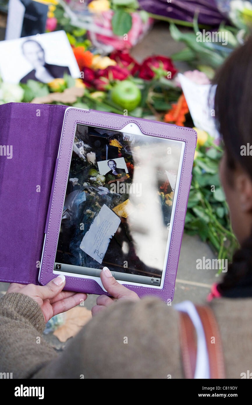A young woman takes a picture of the tributes to the late Steve Jobs ...