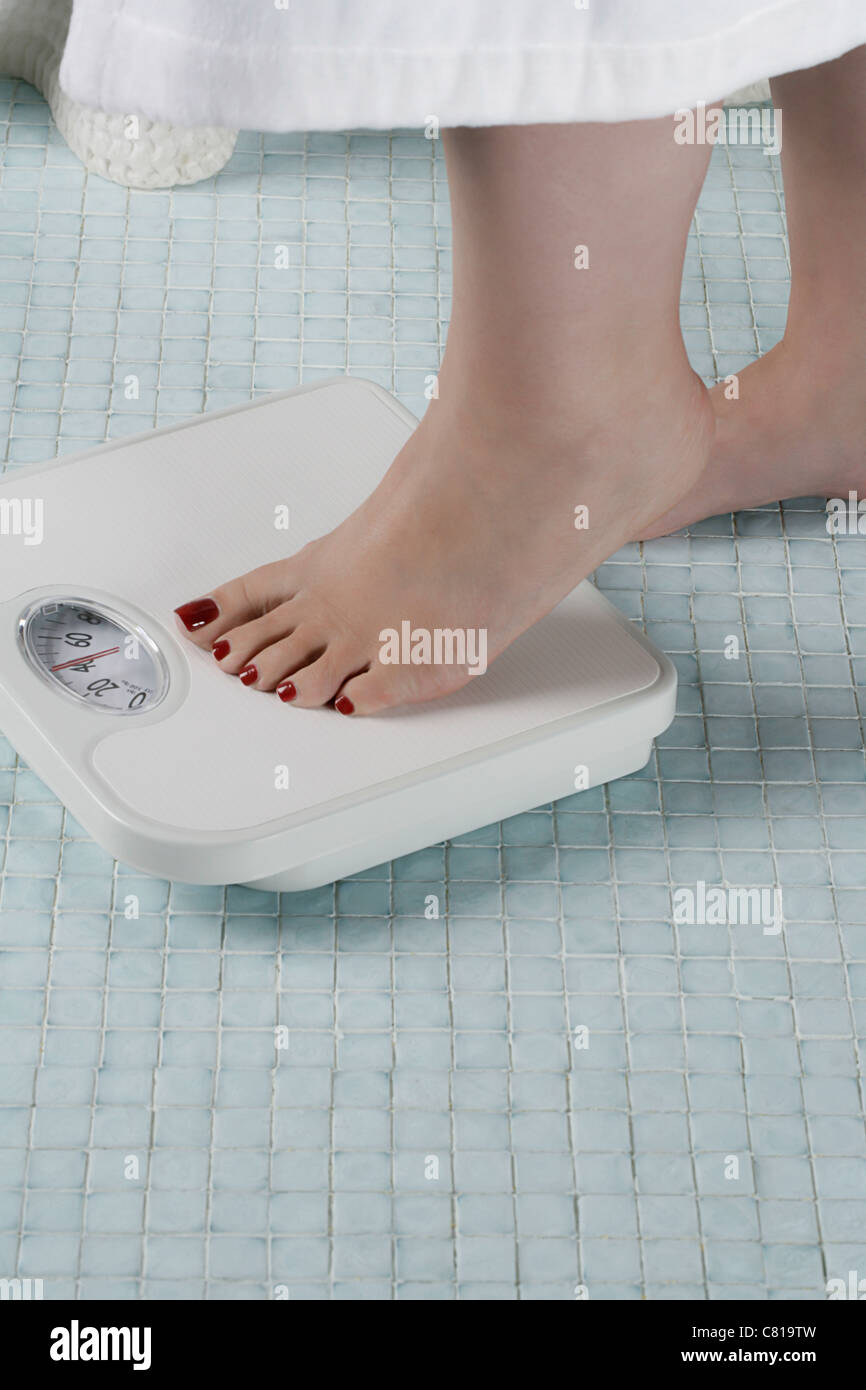 Woman stepping onto bathroom scale Stock Photo - Alamy
