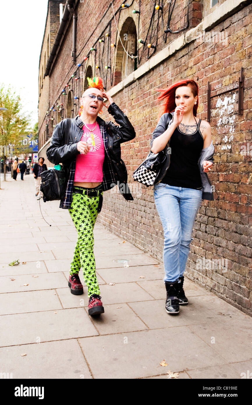 London Camden Town Stables market young punk couple walking pavement he ...