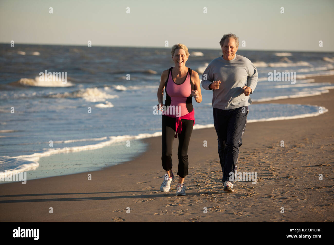 Couple running together on beach Stock Photo - Alamy