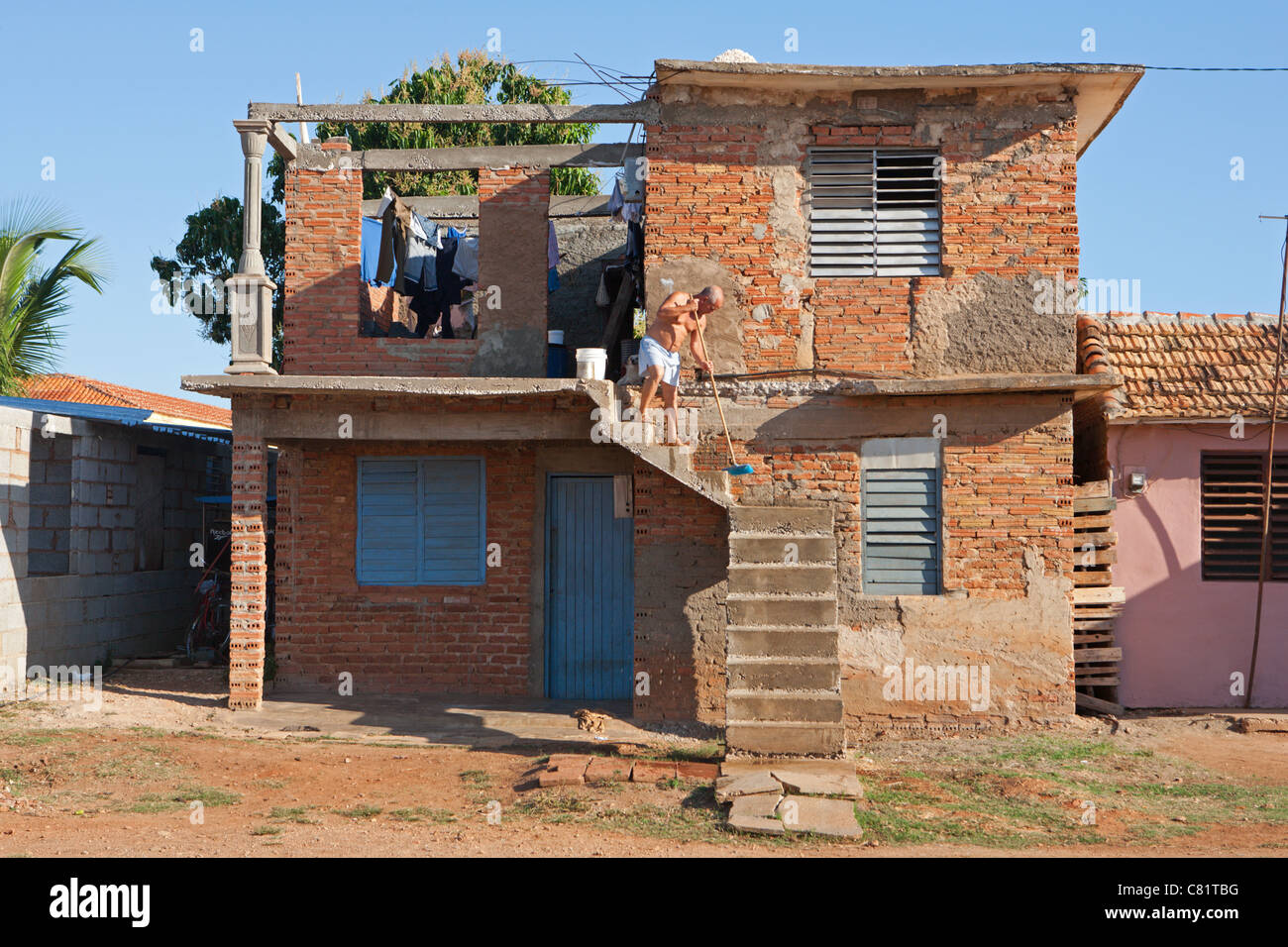 TRINIDAD: MAN SWEEPING STEPS DILAPIDATED HOUSE Stock Photo - Alamy