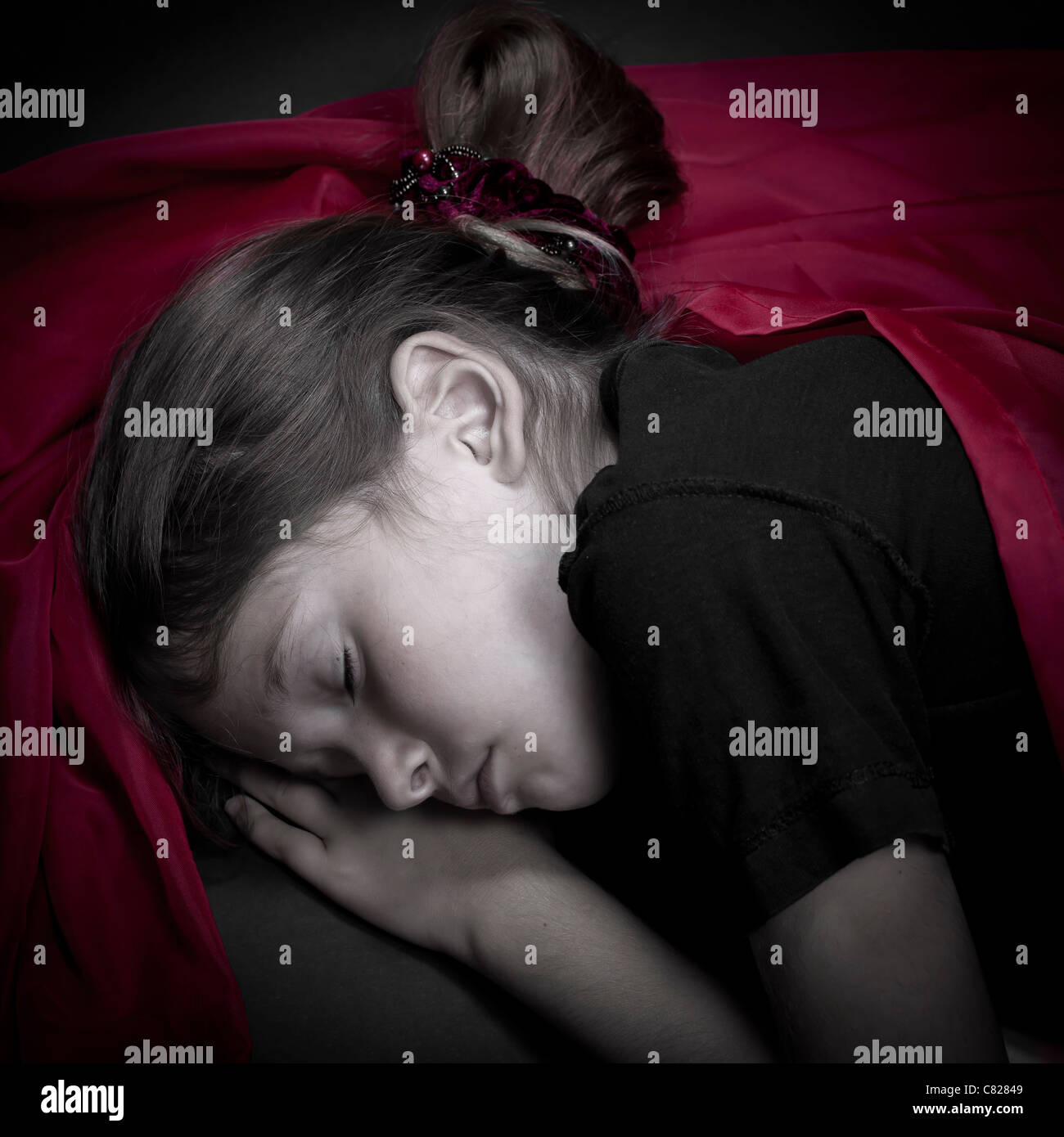 a girl is curled up asleep in a red cloth Stock Photo - Alamy