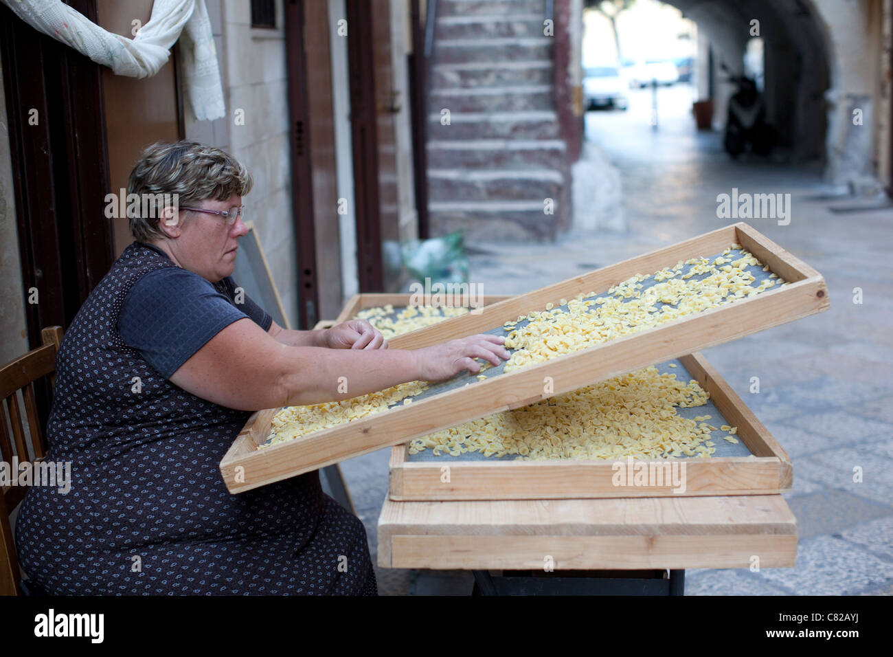 Woman making pasta on the Medieval streets of Bari old town, Puglia ...