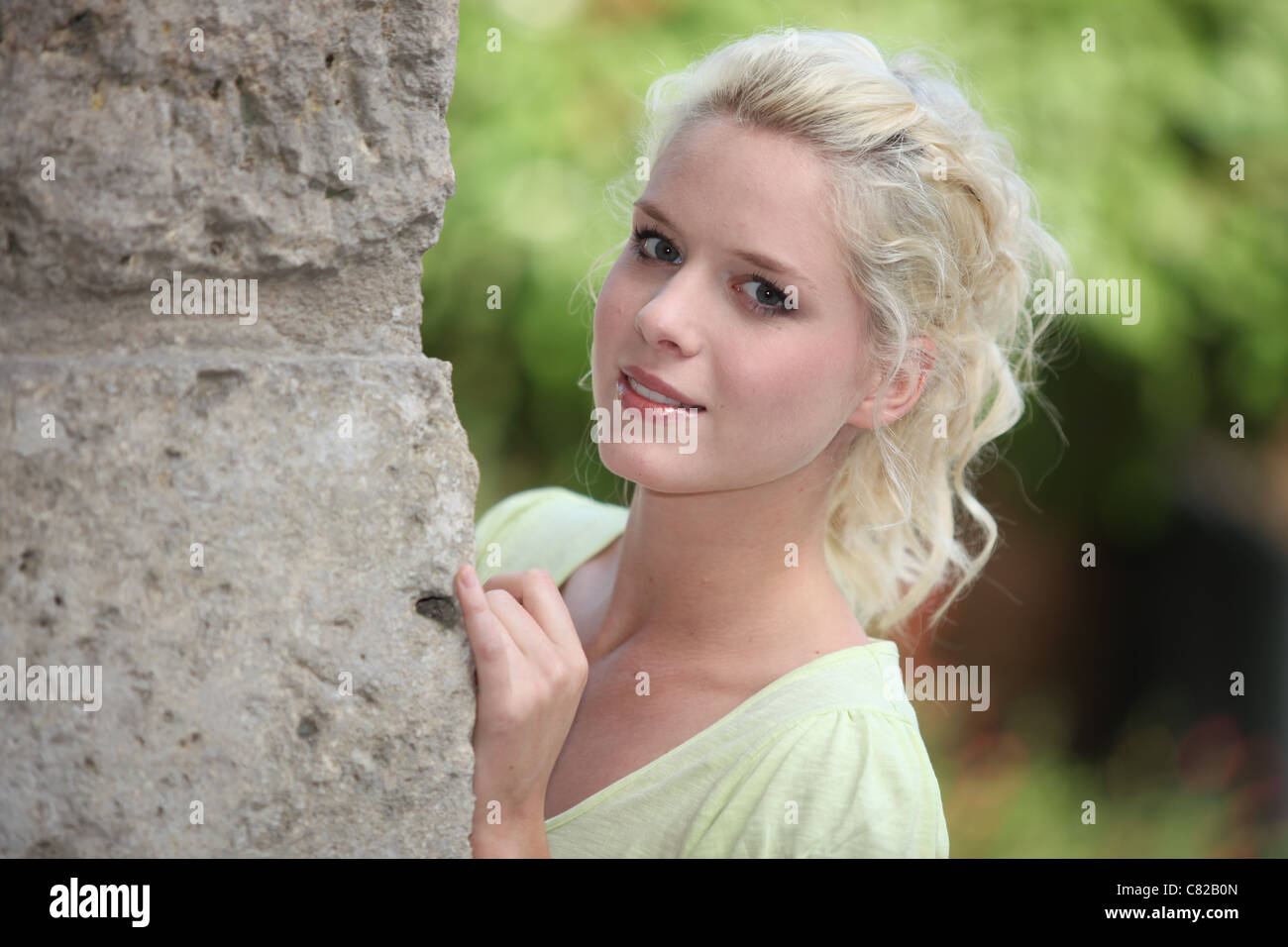 Girl hiding behind a stonewall Stock Photo - Alamy