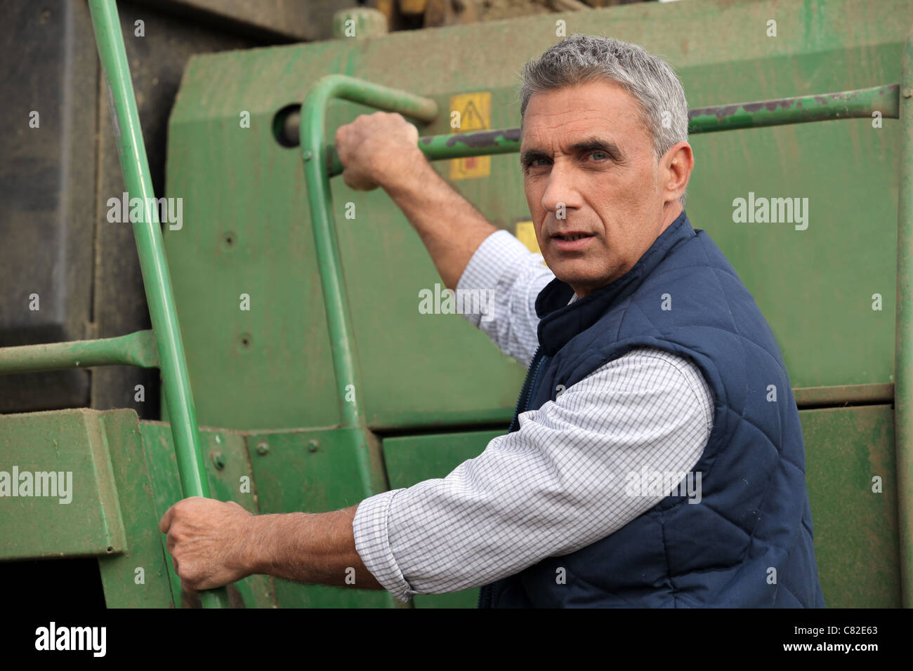 Farmer climbing into a tractor Stock Photo - Alamy