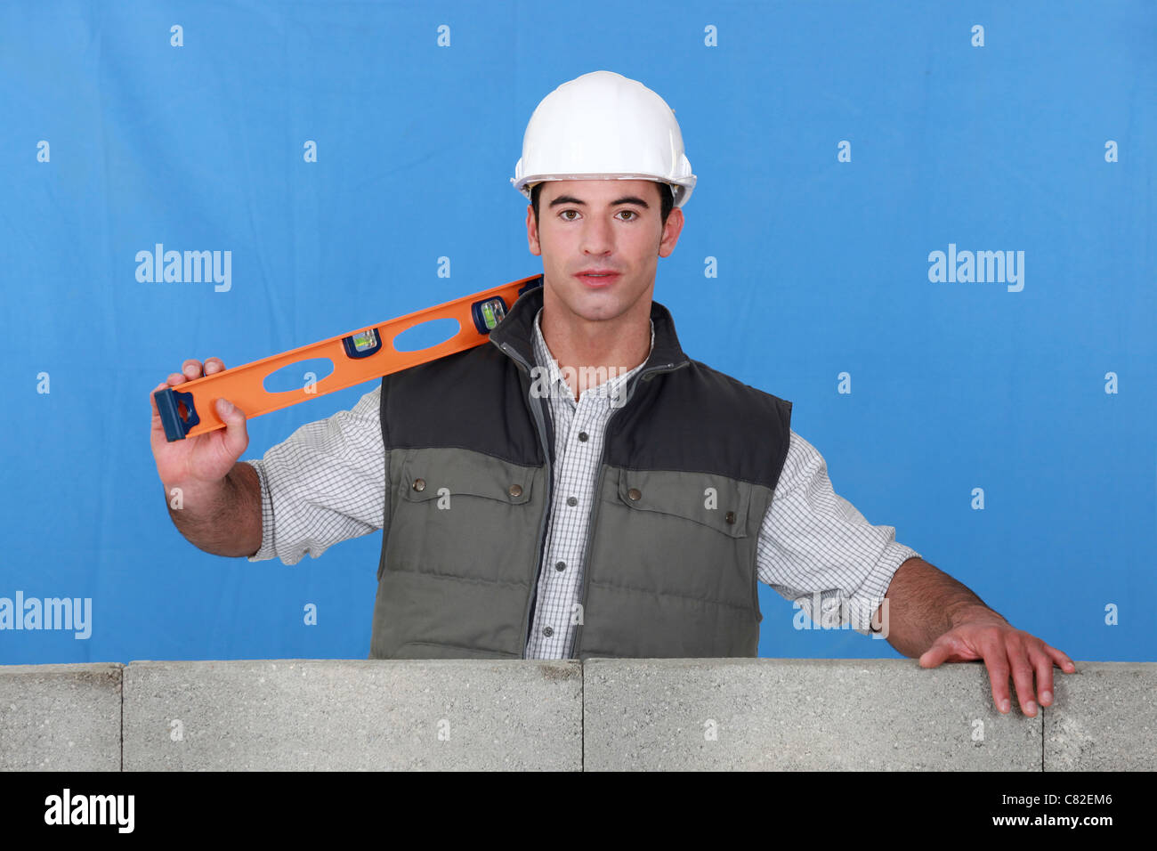 Man stood by wall with spirit-level Stock Photo - Alamy